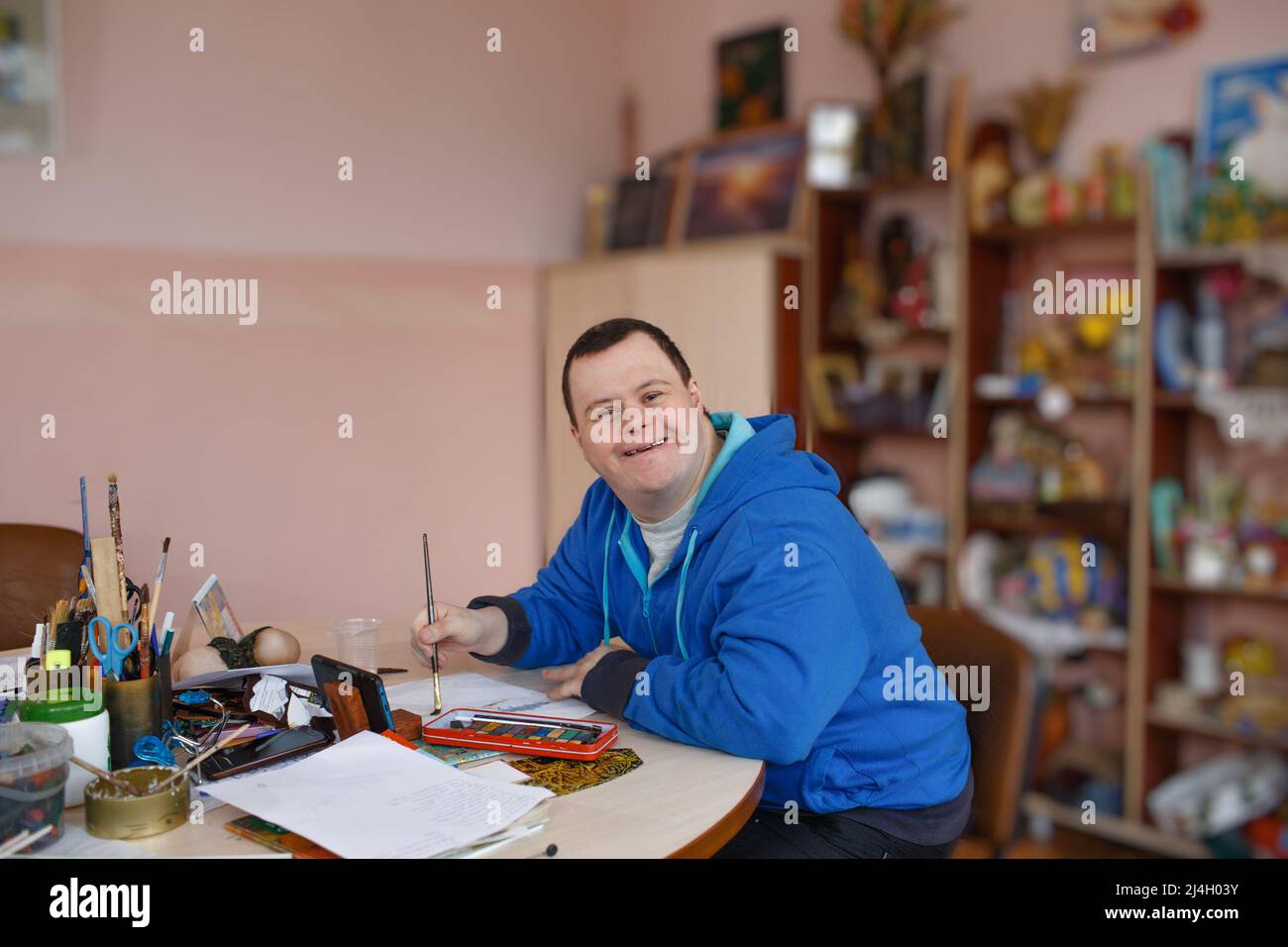 an adult man with down syndrome is engaged in drawing in a workshop ...