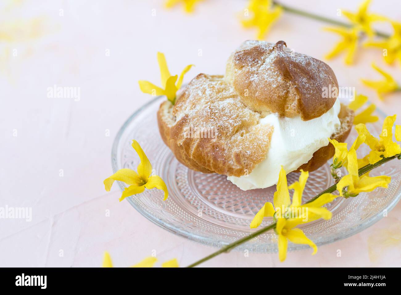 Choux Bun with whipped cream and sugar powder on top on glass plate ...