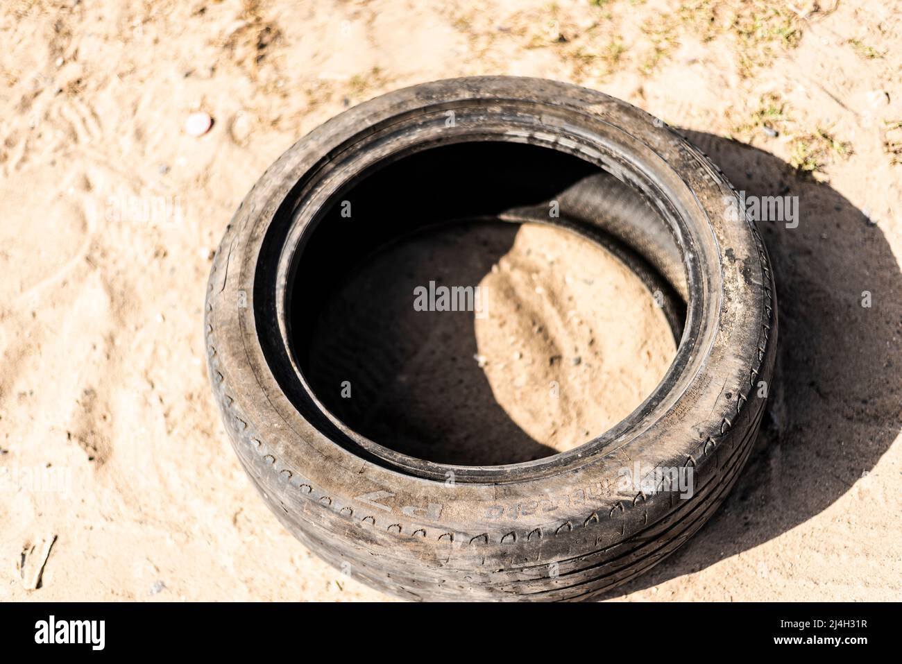 Portrait of a bad old tire lying on the sand floor. City of Salvador in ...