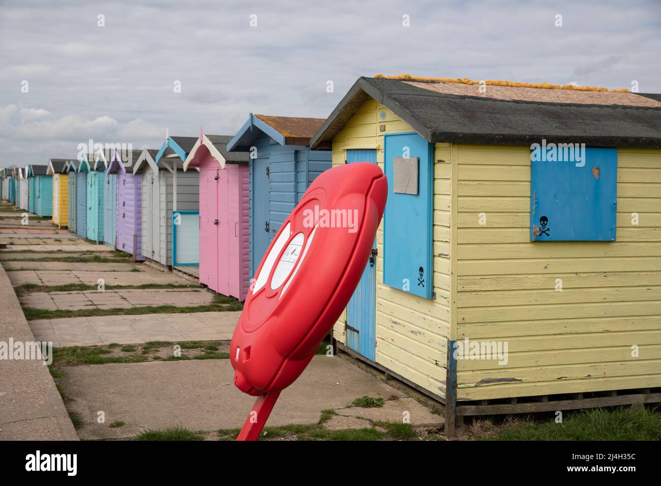 A row of brightly-coloured beach huts on the seafront / promenade at ...