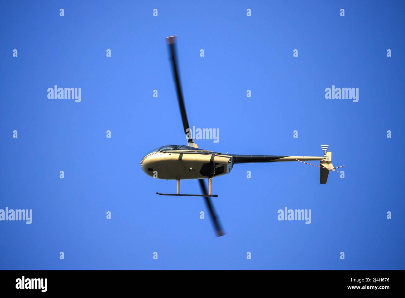 The helicopter Robinson R44 flies in the blue sky Stock Photo - Alamy