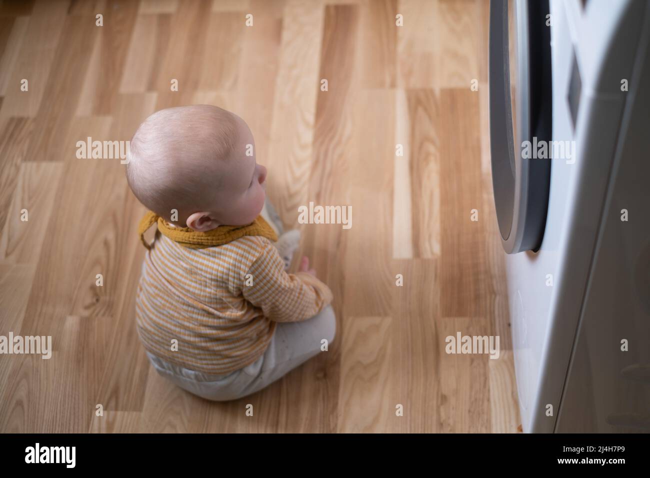 Little curious caucasian girl playing with washing machine watching on ...