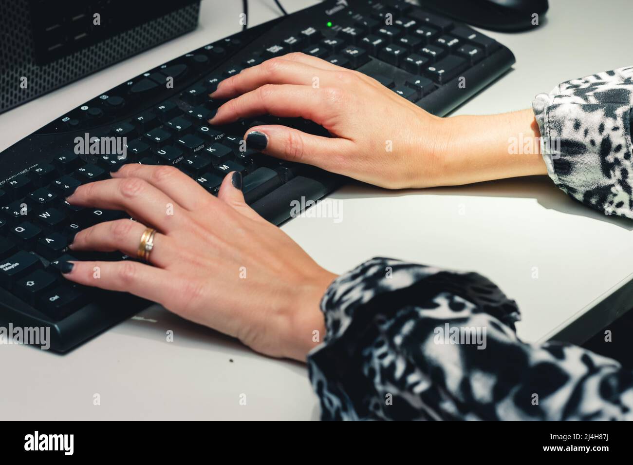 closeup caucasian hands of female worker with black nails, typing on ...