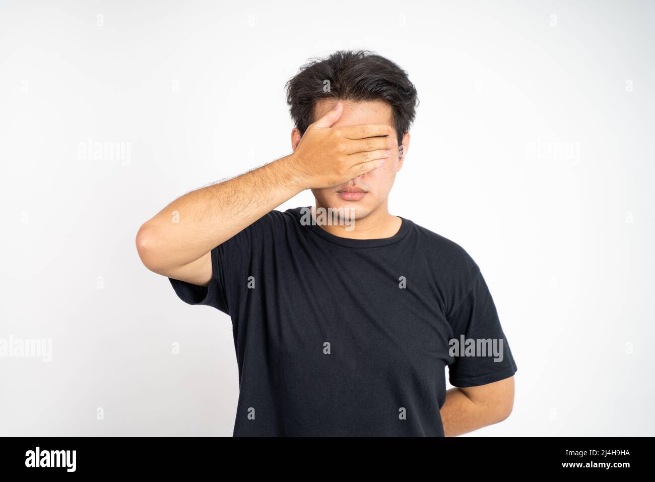 young man with hands covering eyes standing Stock Photo - Alamy