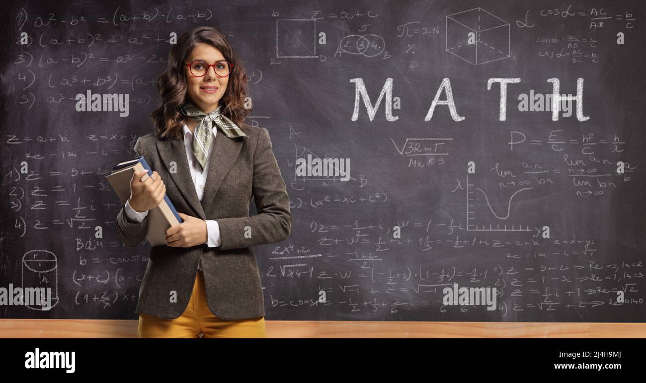 Young female math male teacher holding books and posing in front of a ...
