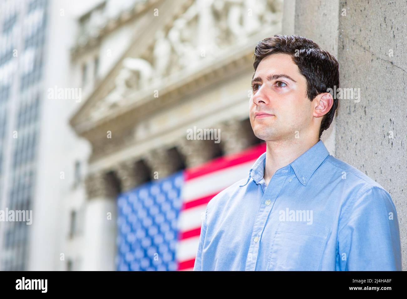 A young guy is sincerely looking forward. There is American flag in the ...