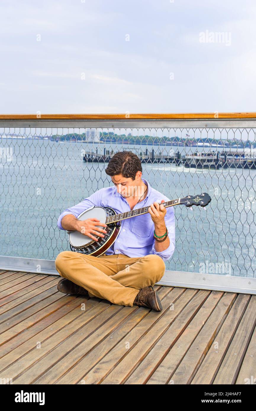 Lowering his head, crossing legs and thinking, a young musician is ...