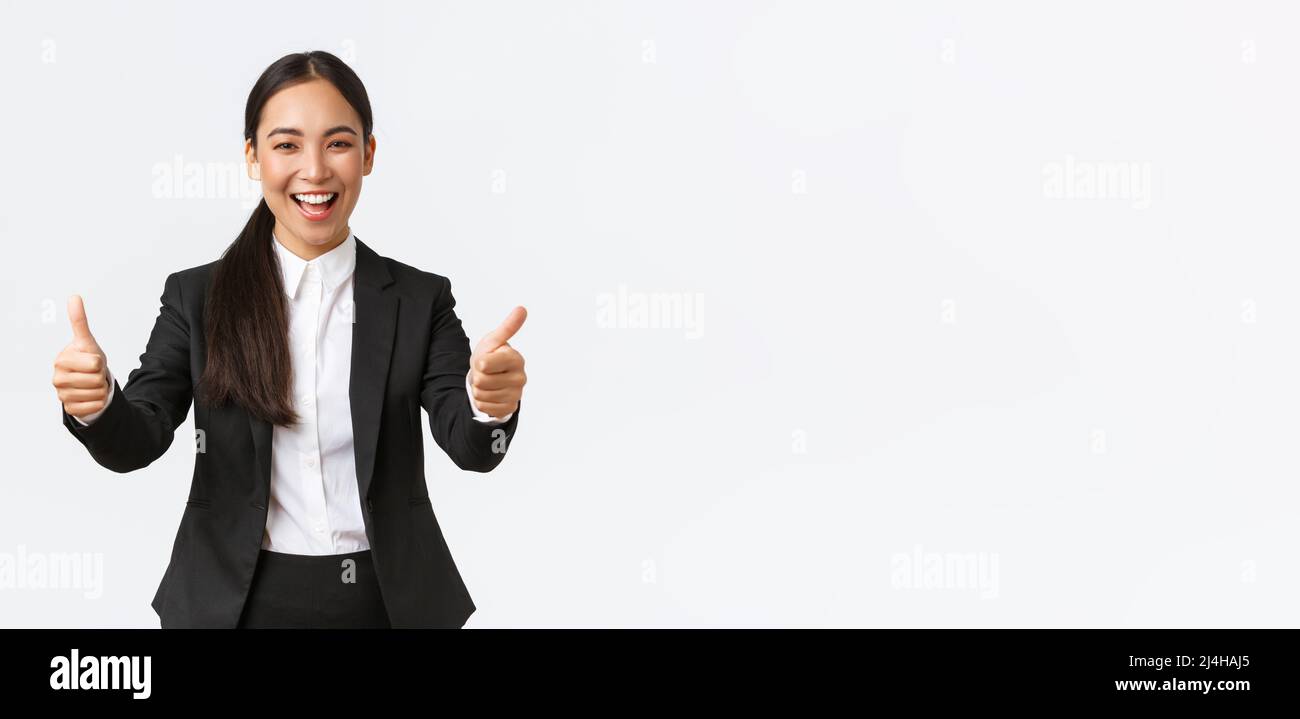 Successful upbeat asian businesswoman showing thumbs-up and smiling ...