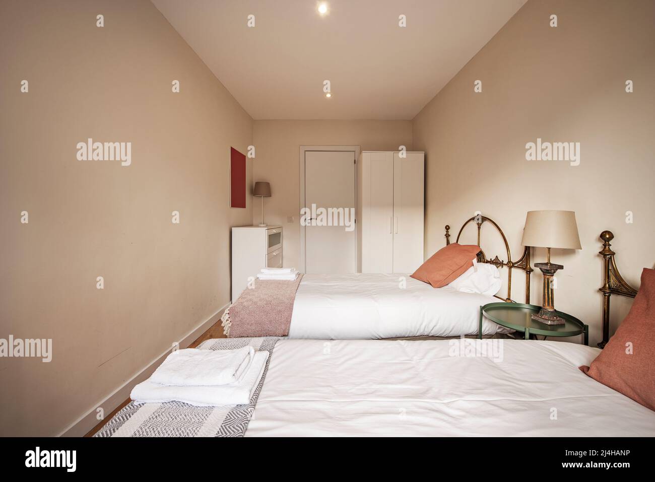 Bedroom with separate beds with brass headboards, white wardrobe and ...
