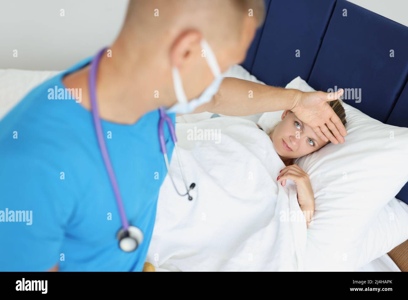 Doctor touches forehead of sick woman in bed Stock Photo - Alamy