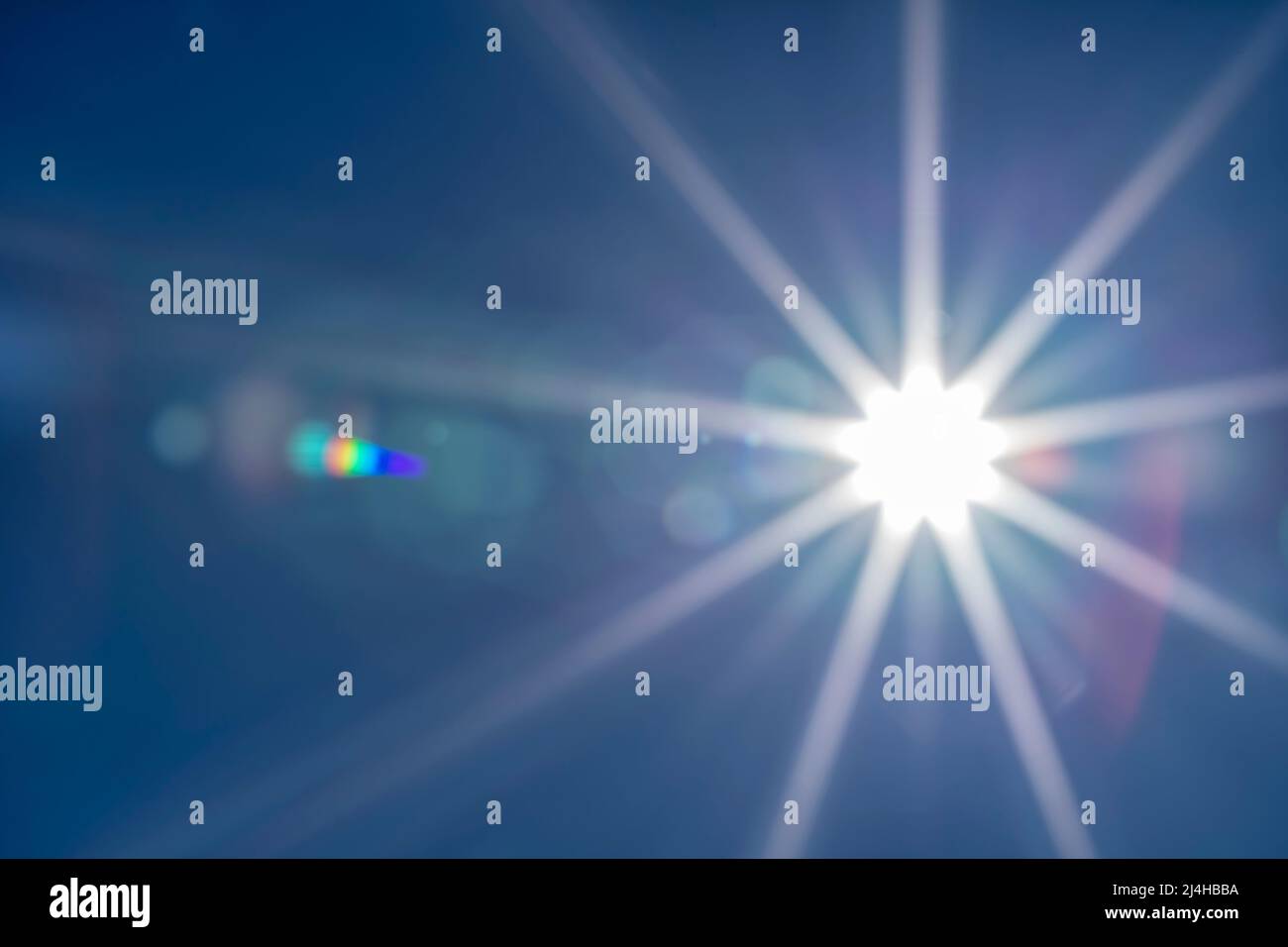 The sun in the blue sky with reflections in the lens of the photo ...