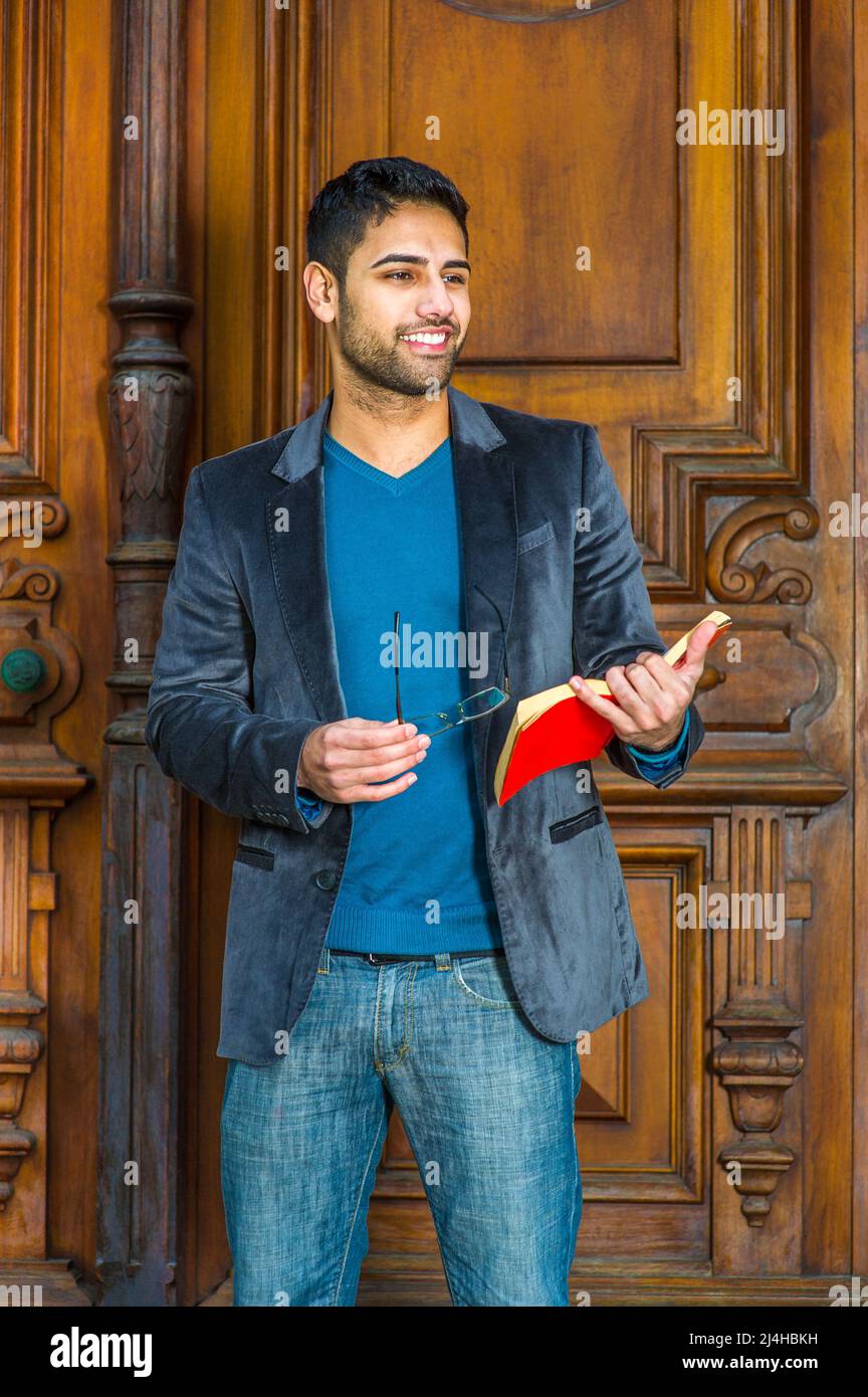 Dressing in a blue woolen blazer, knit sweater and jeans, holding ...