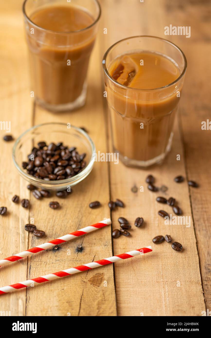 Iced coffee in transparent glasses with ice and straws, on a wooden background, a cooling drink ...