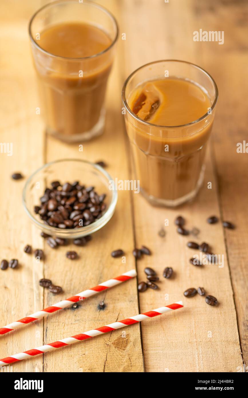 Iced coffee in transparent glasses with ice and straws, on a wooden ...