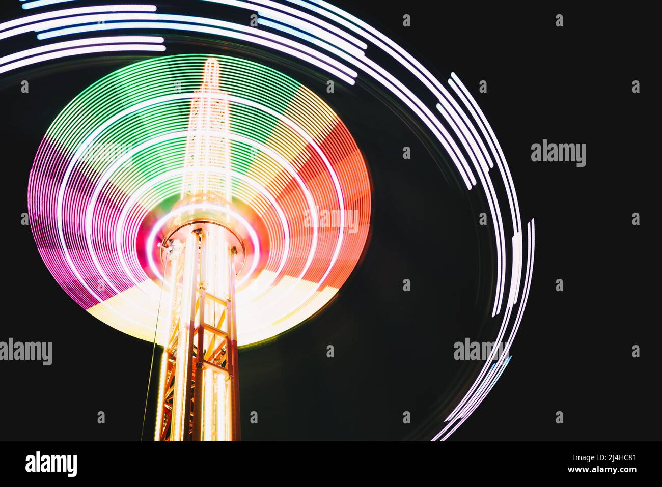 Multicolored Star Flyer tall Carousel rotating on long chains in an ...