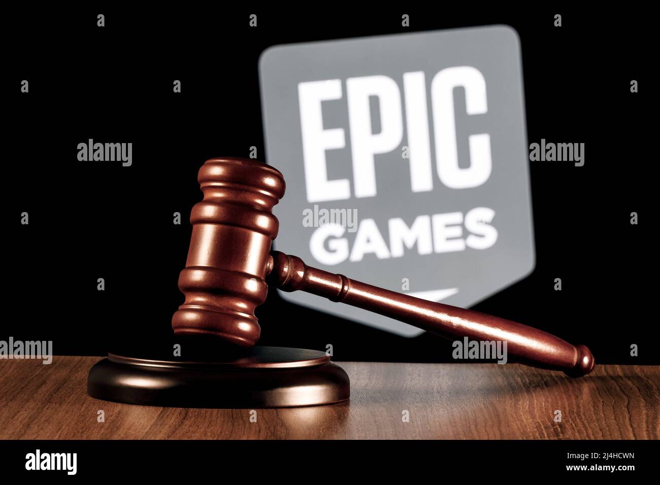 Gavel on table against the background of Epic Games company logo. The ...