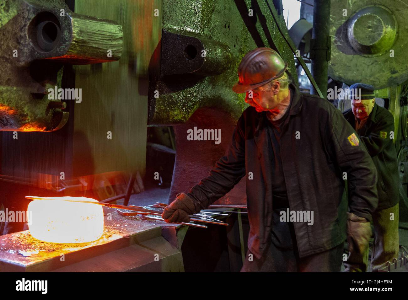 blacksmith worker forging large piece of hot steel in old factory Stock ...