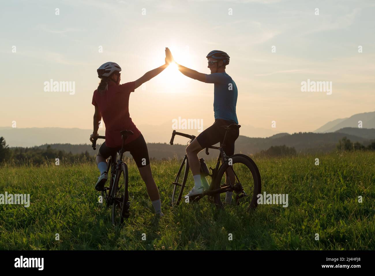 Road cycling couple giving a high five to each other and enjoying ...