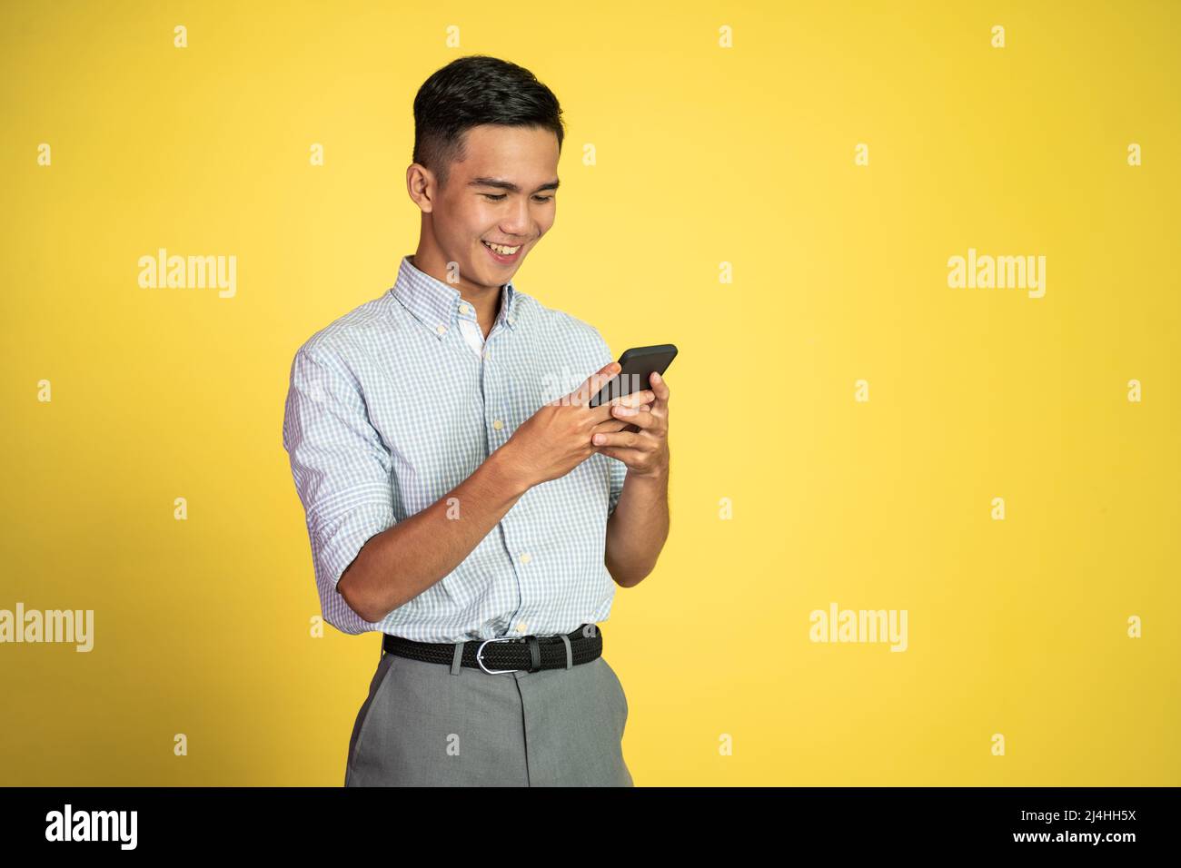 happy asian young man looking at the screen of a mobile phone Stock ...