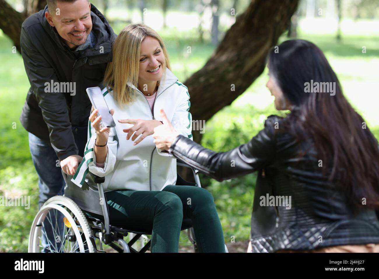 Friends chat in park one woman in wheelchair Stock Photo - Alamy