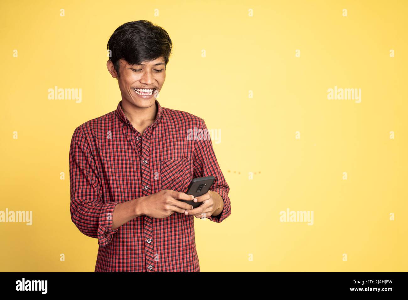 happy asian young man looking at the screen of a mobile phone Stock ...