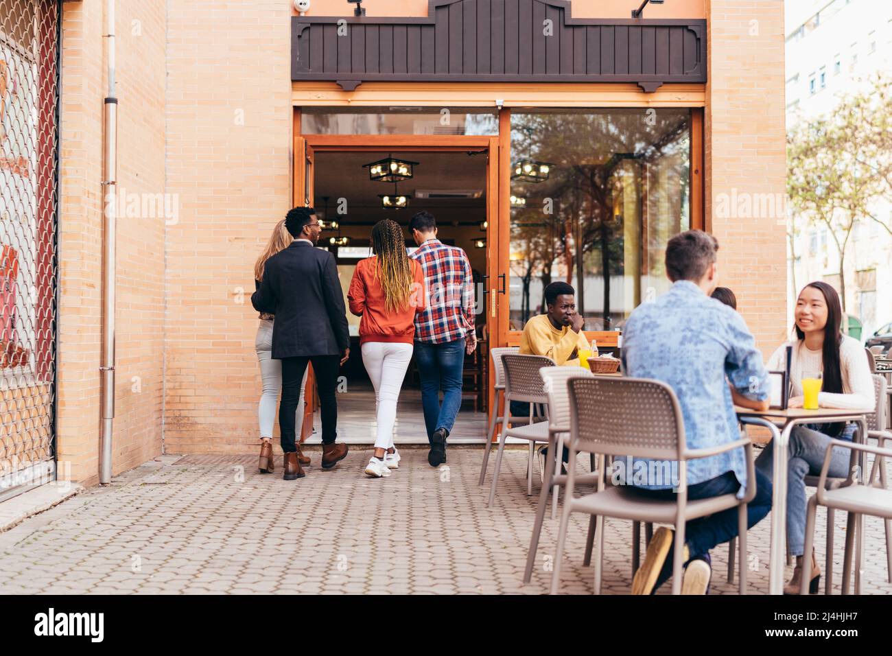 4 multiethnic people arriving at a restaurant Stock Photo - Alamy