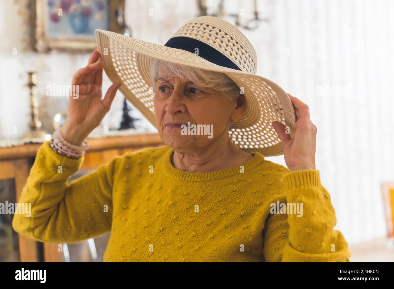 ready for summer - senior woman in hat at home medium closeup living ...