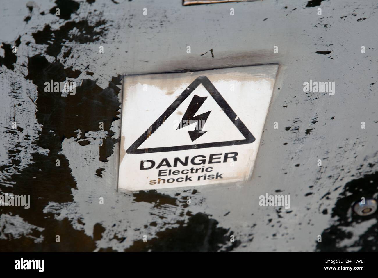 A black and white "Danger electric shock risk" sign on a wall with ...
