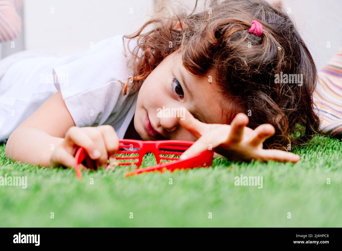 A girl lying on the grass with her face pressed to the ground is ...