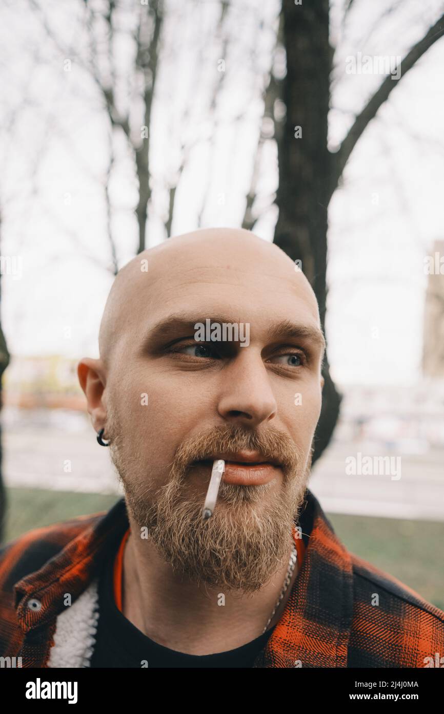 Guy smoking a thoughtful cigarette. Guy dressed casual and beard bald ...
