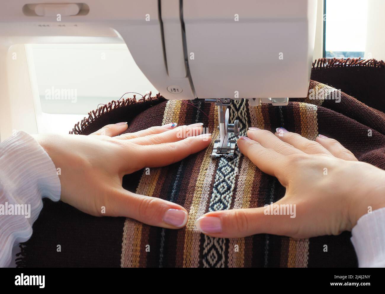 Woman's hands in the process of sewing a colored cloth on the sewing ...