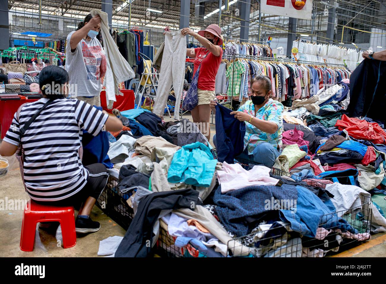 Bargain hunters. Women sorting through bargain priced clothes in a ...