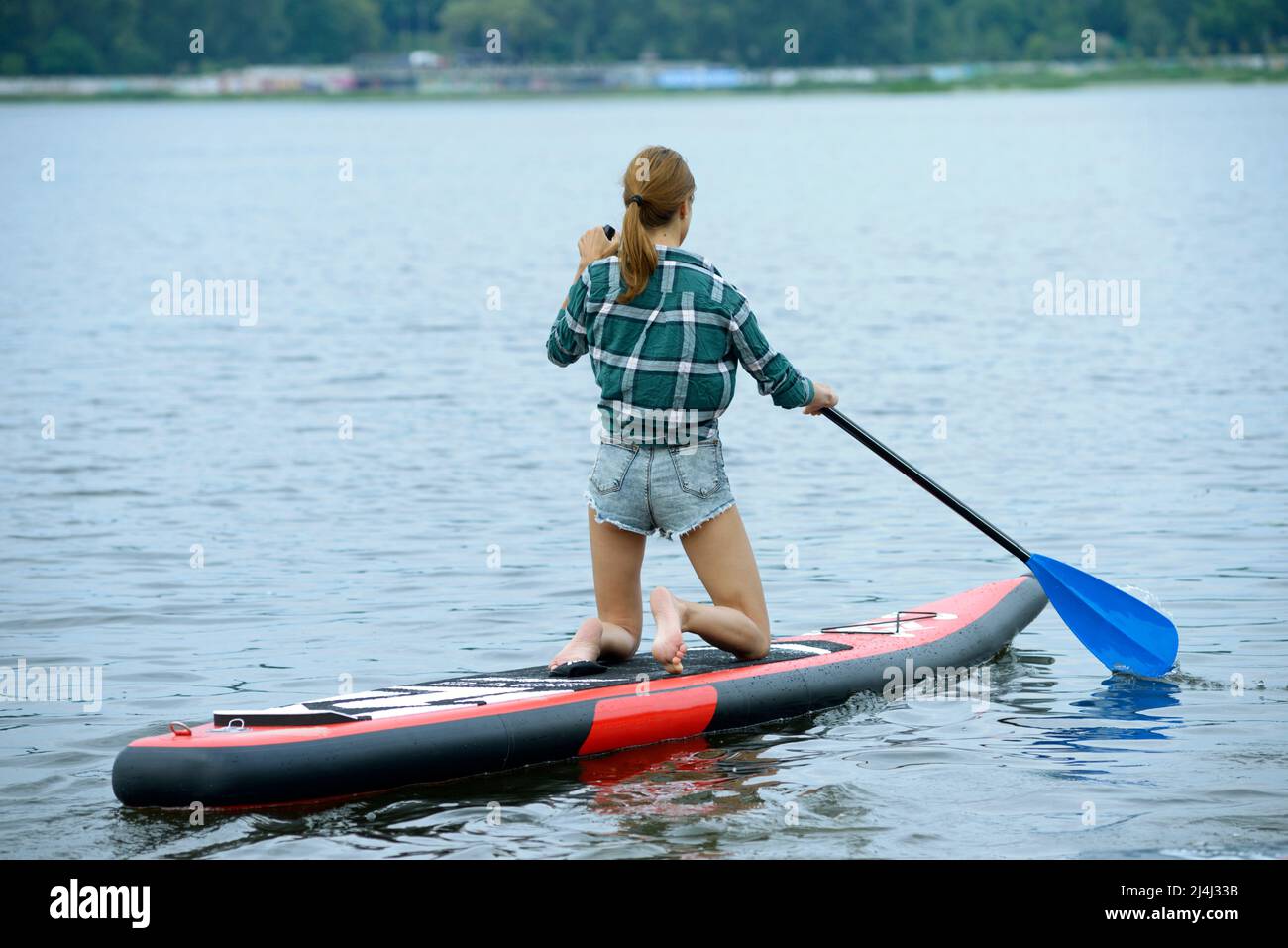 Girl rowing SUP board on water, kneeling Stock Photo - Alamy