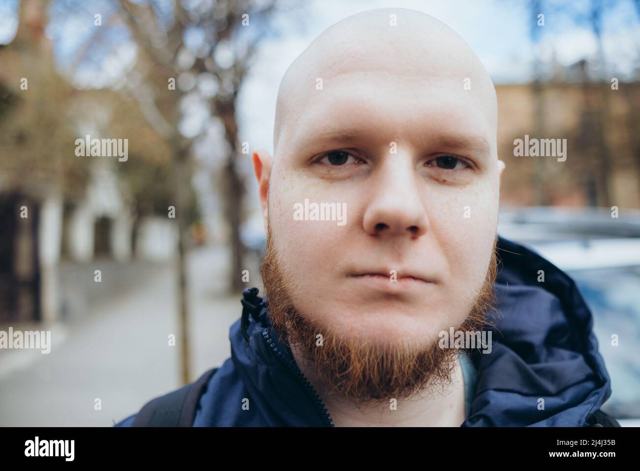 A white man with bald head and beard has a rest in a park, close-up ...
