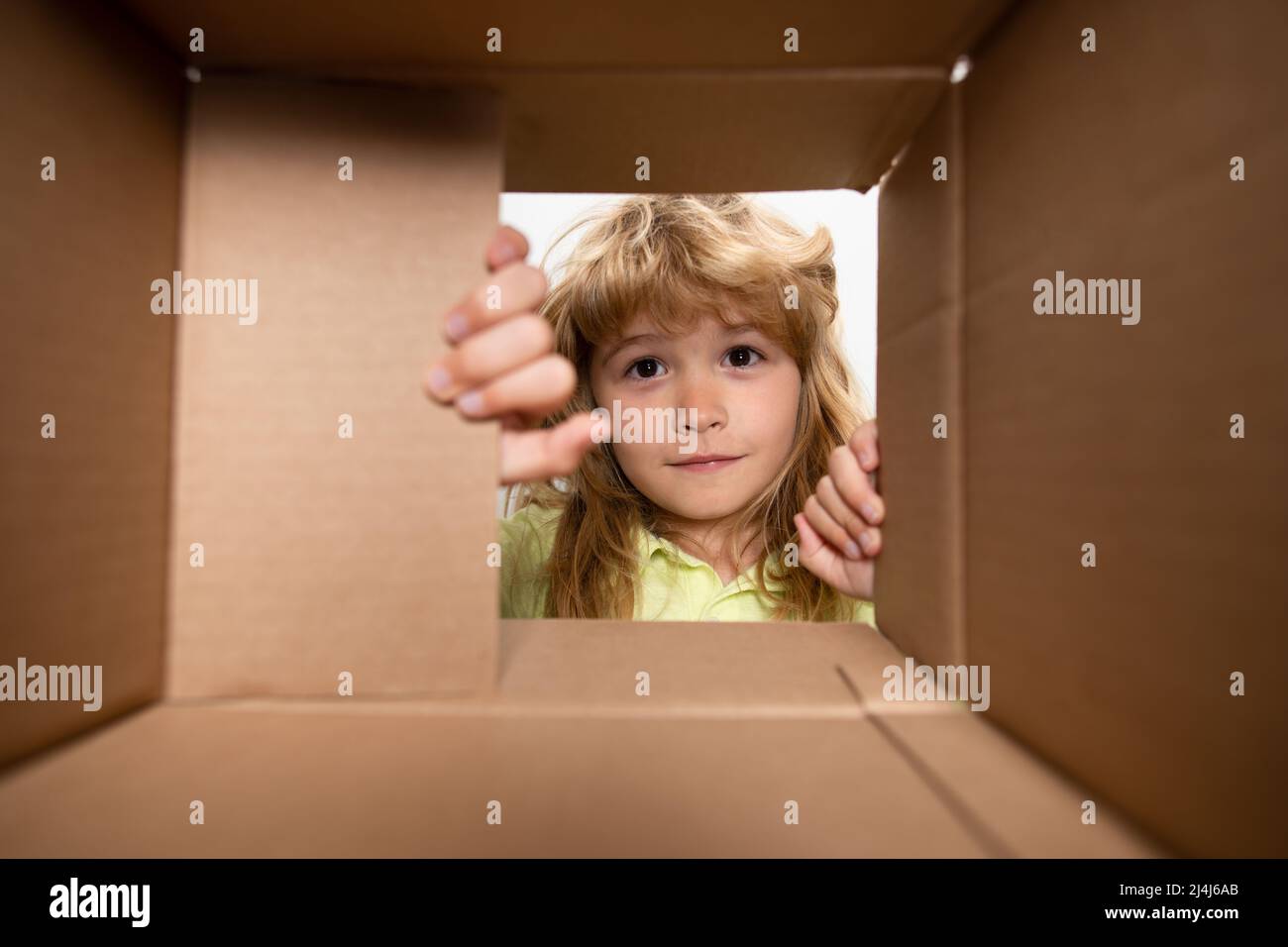 Surprised child boy unpacking, opening carton box and looking inside ...