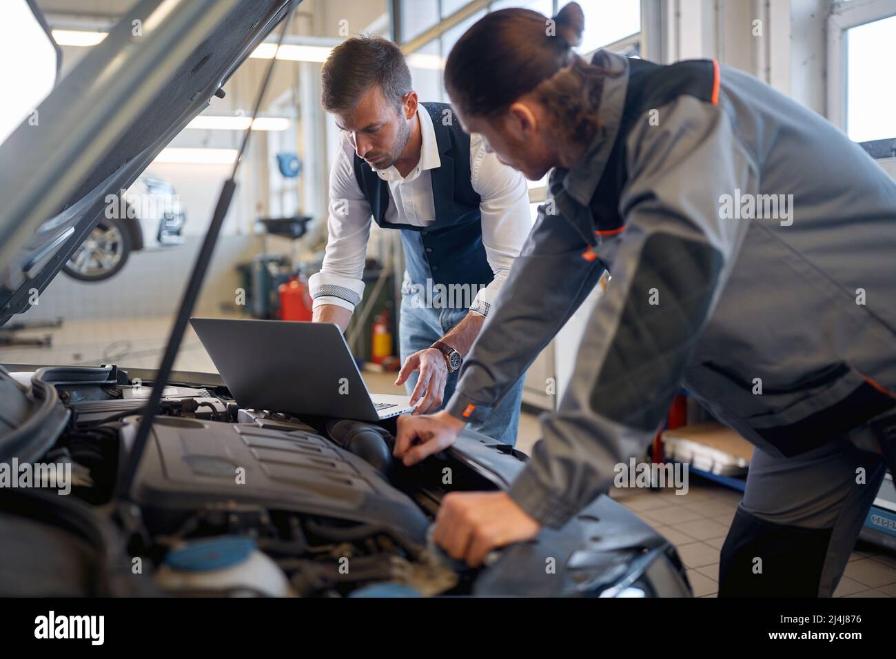 Two men in auto service repairing a car engine Stock Photo - Alamy