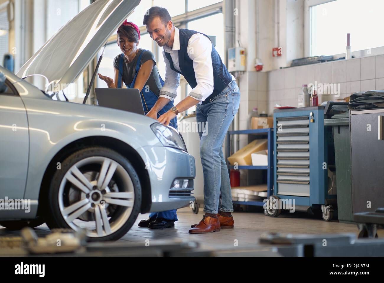 Cheeerful man and woman working in car workshop Stock Photo - Alamy