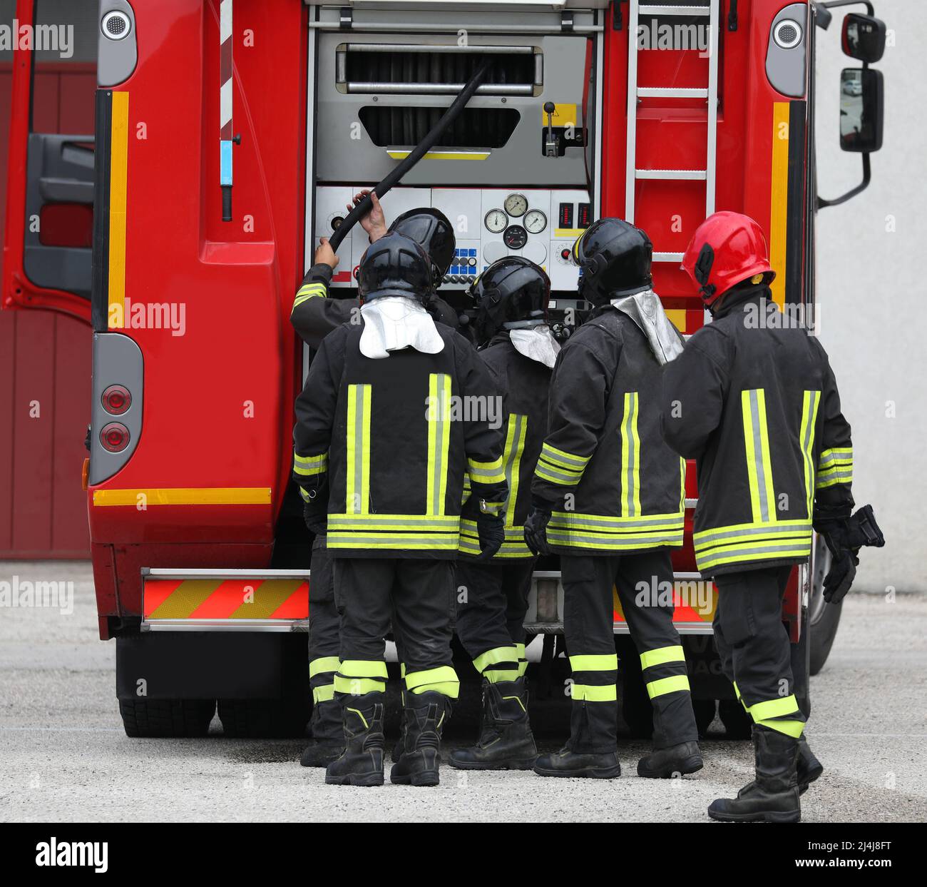 five firefighters with uniform and the fire truck during the emergency ...