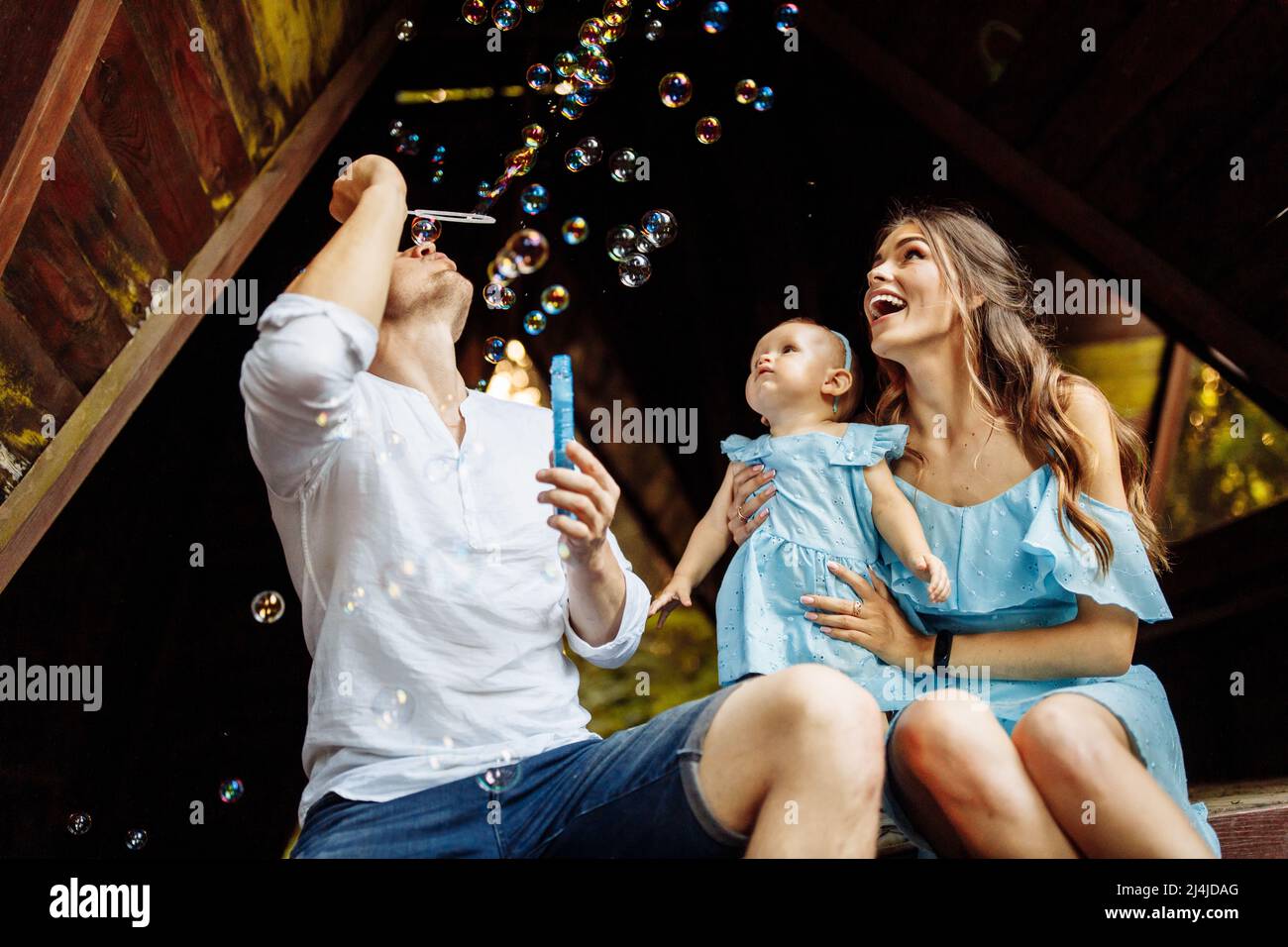 Happy family play outdoor, caring father blow the bubbles for baby girl ...