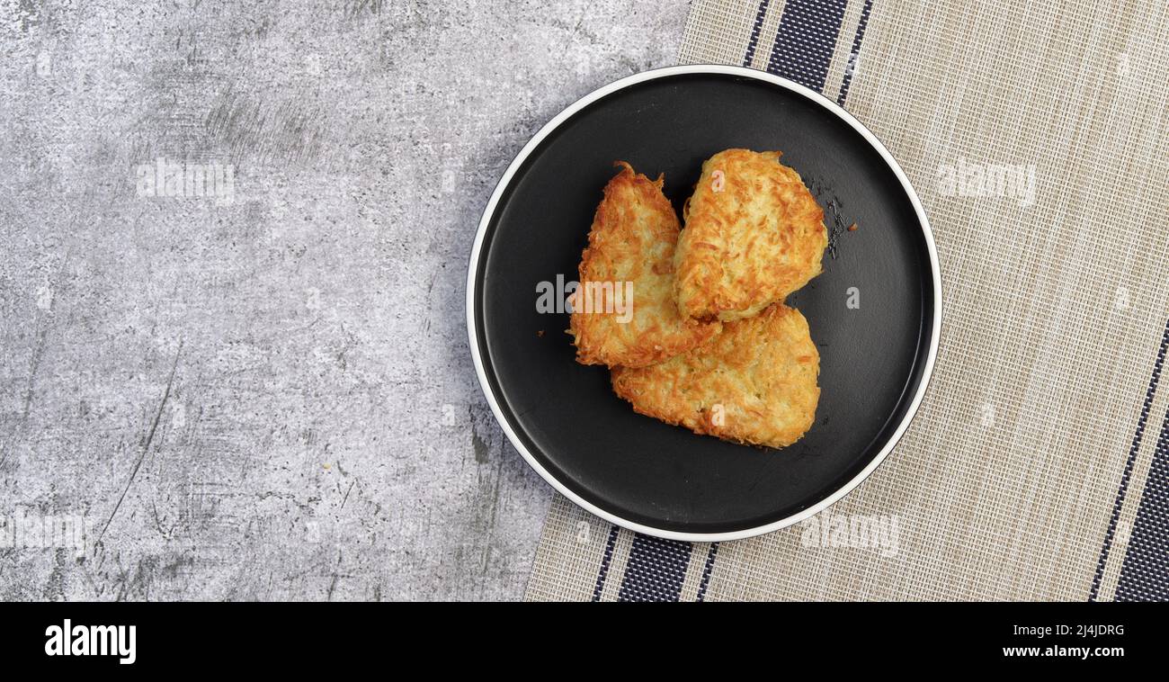 Traditional Hash brown potato fried pancakes on a round plate on a dark ...