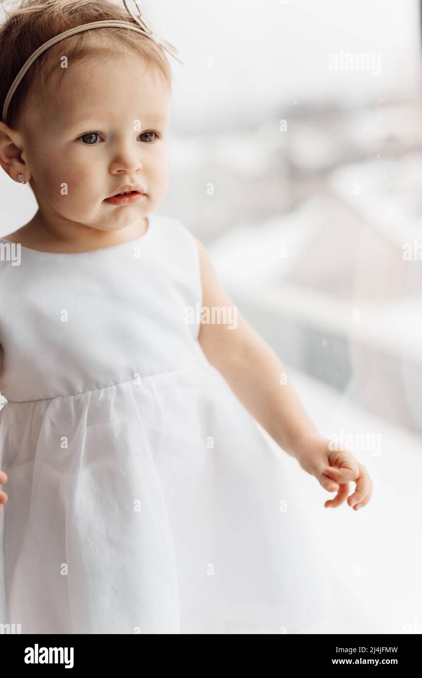 Little blonde positive princess girl in white casual dress and shoes ...