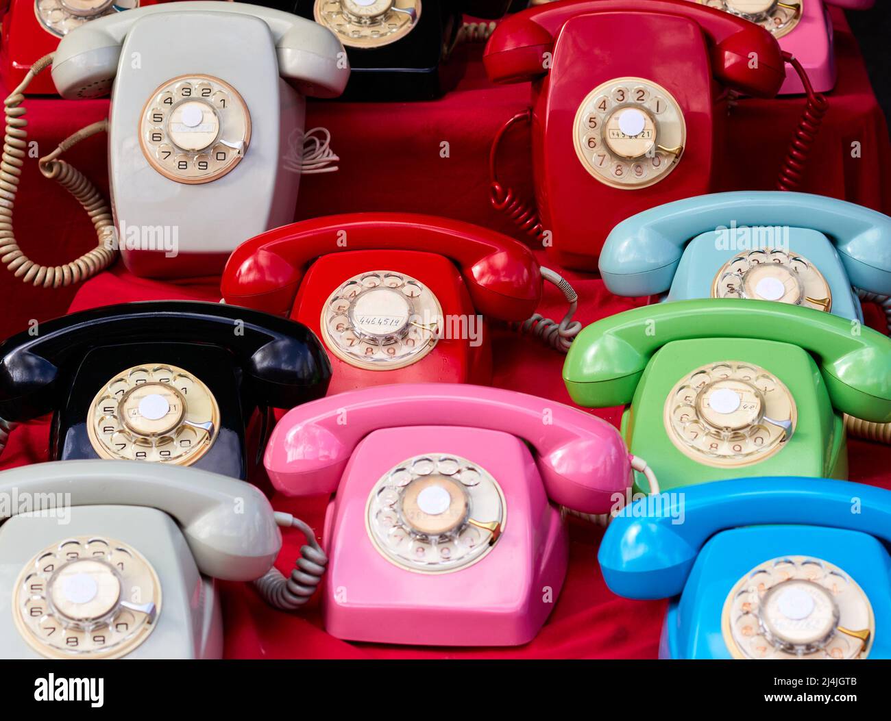 Set of brightly colored rotary phones arranged on a table with a red ...