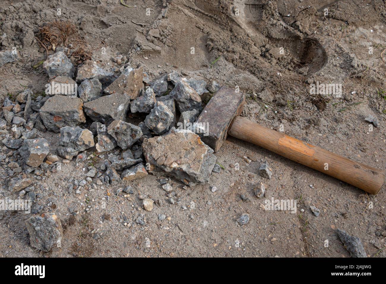 A heavy hammer lying on the ground and smashed concrete for demolition ...