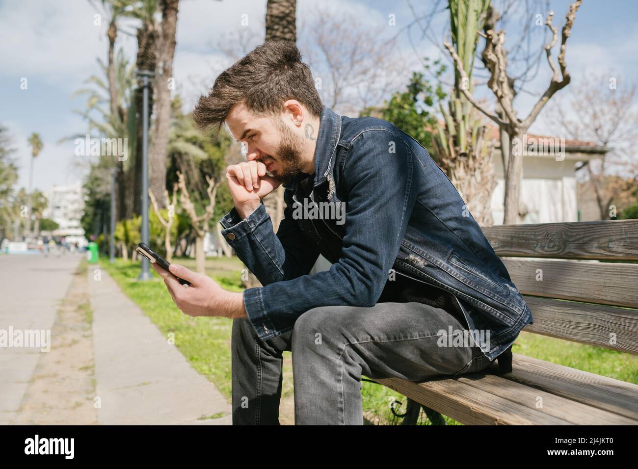 Young man wearing blue jeans jacket receiving bad news on the phone ...