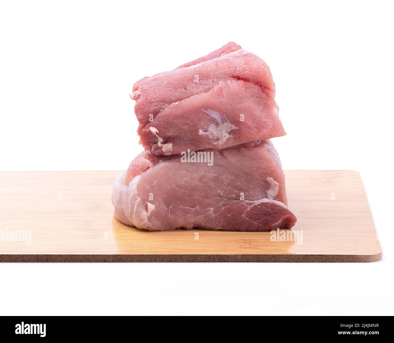 Two pieces of raw pork meat are arranged vertically on a cutting board ...