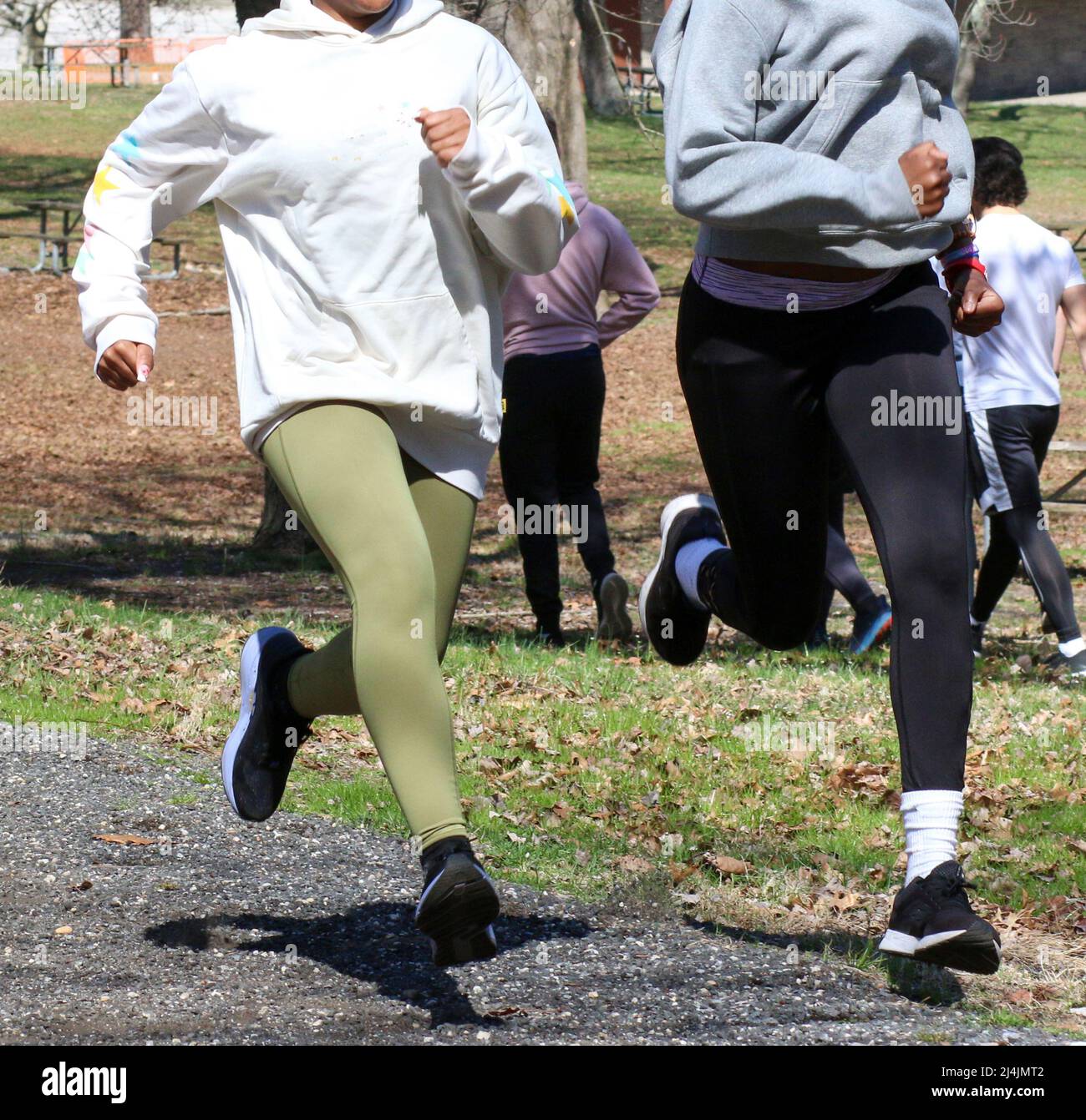 Two high school track and field athletes are running fast on an uphill ...
