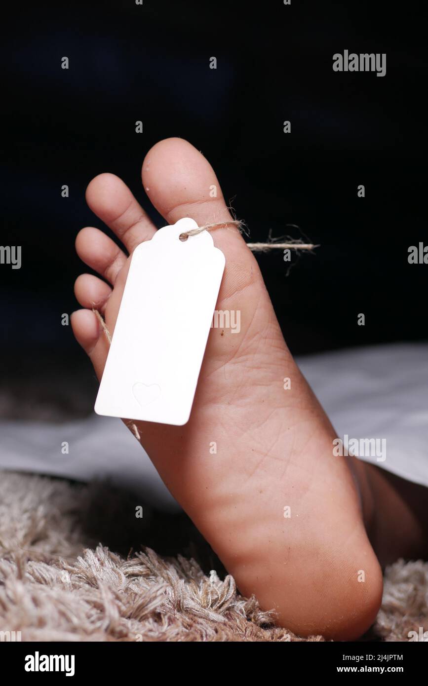 The dead man's body with blank tag on feet under white cloth in a ...