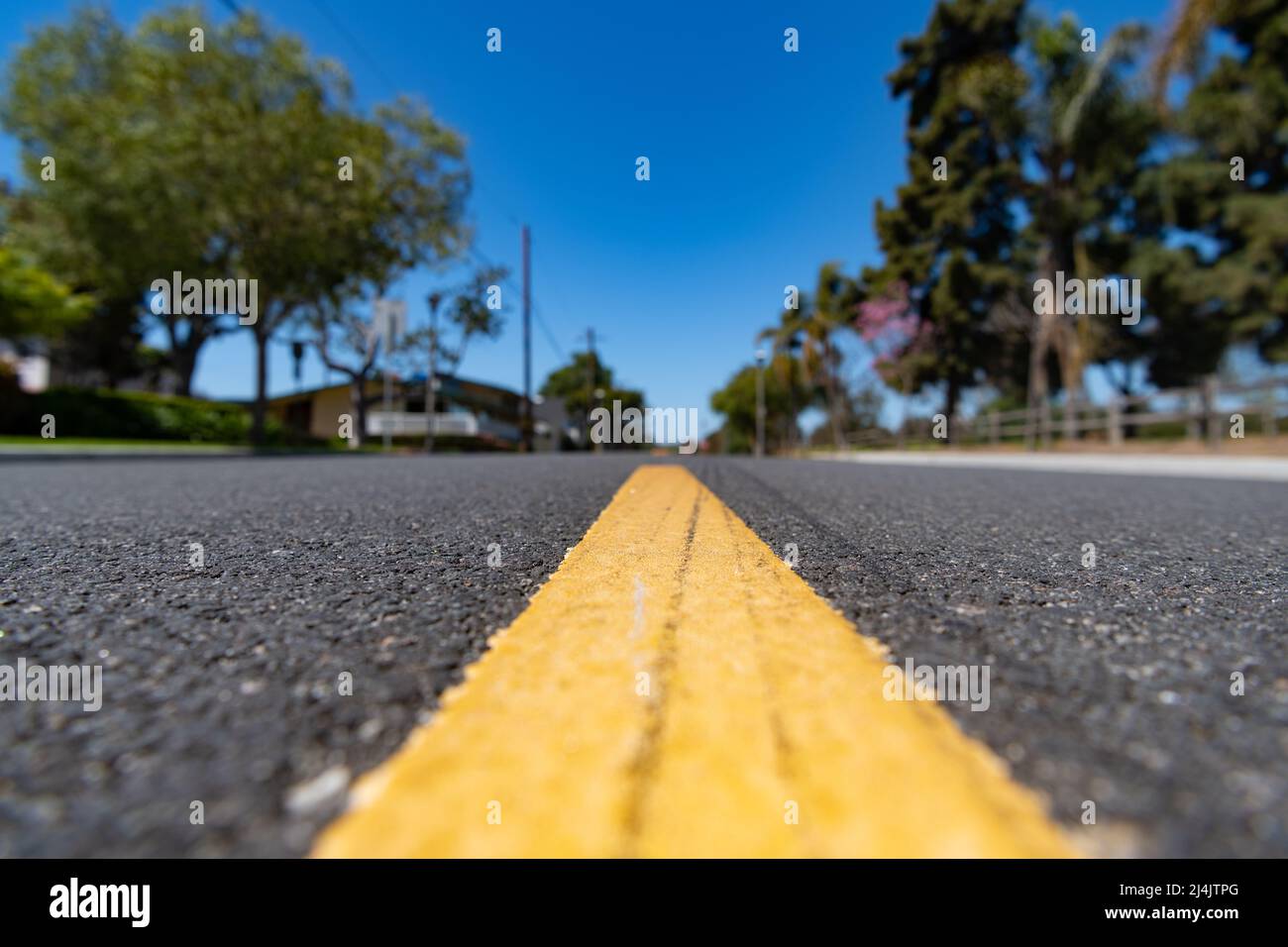 Yellow line road marking on asphalt road surface along blurry ...