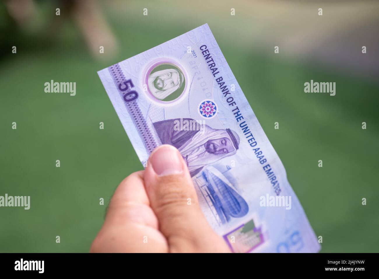 Persons hand giving the Currency of the United Arab Emirates (UAE ...