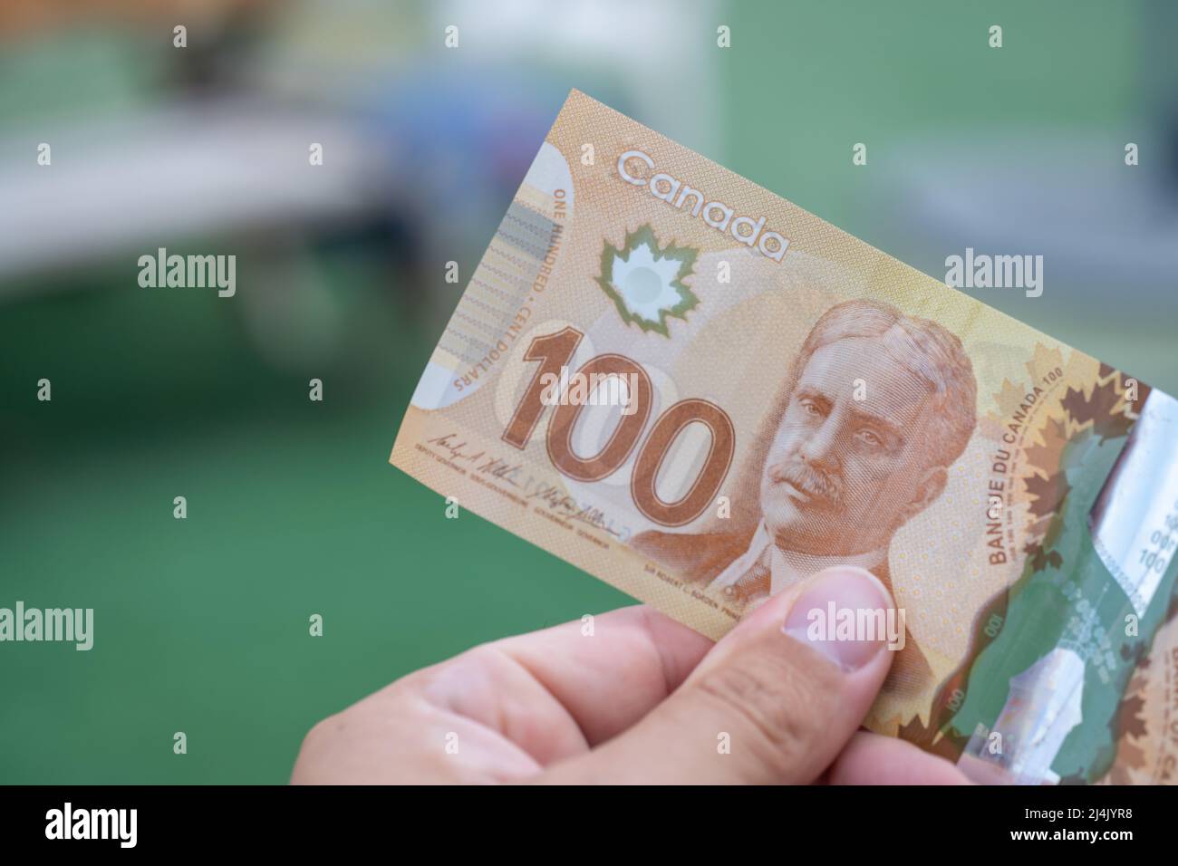 Close up of red Canadian hundred (100) dollar bill with blurred ...